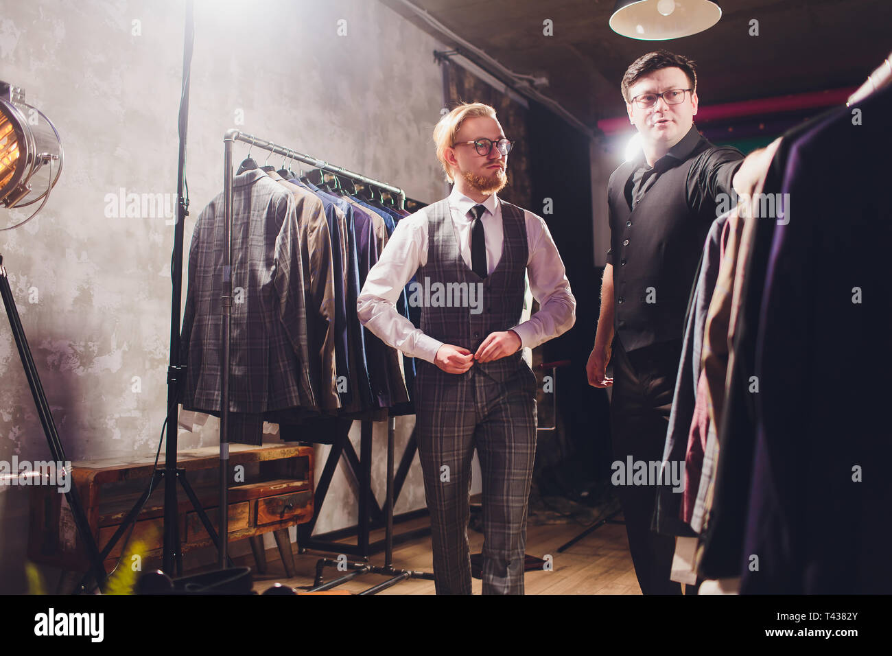 Male customer at shopping mall trying business clothes, shop assistant ...