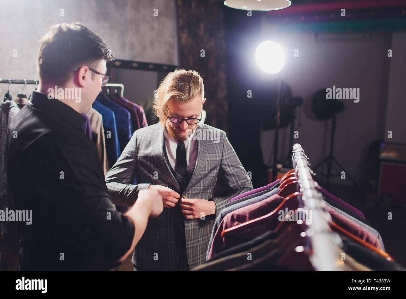 Male customer at shopping mall trying business clothes, shop assistant ...