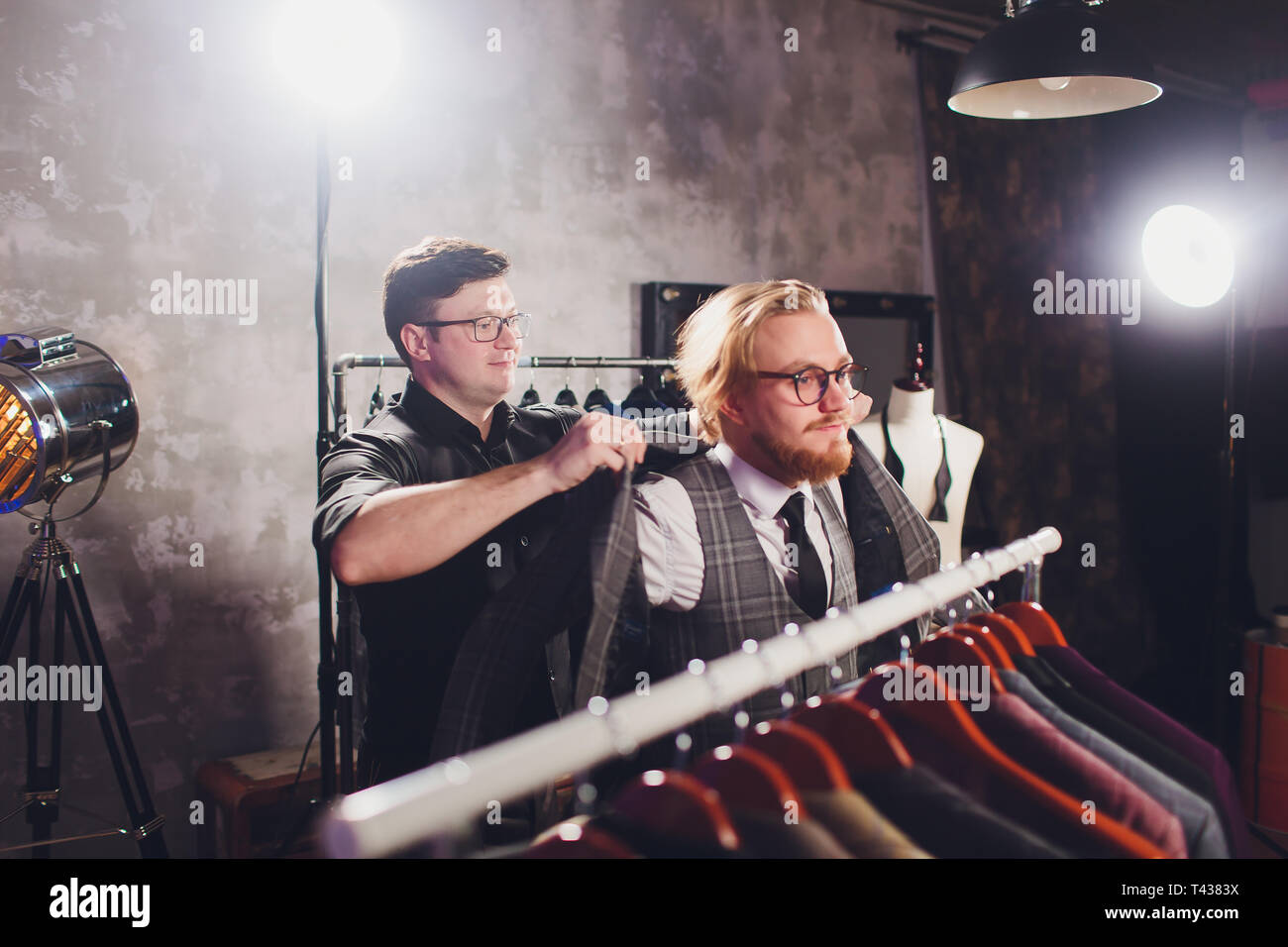 Male customer at shopping mall trying business clothes, shop assistant ...