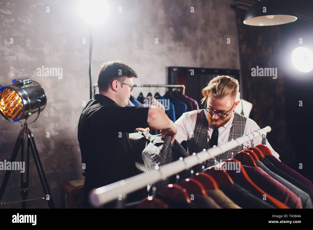 Male customer at shopping mall trying business clothes, shop assistant ...