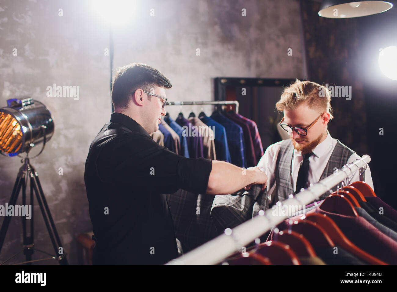 Male customer at shopping mall trying business clothes, shop assistant ...