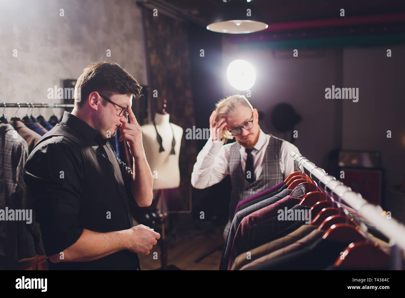 Male customer at shopping mall trying business clothes, shop assistant ...