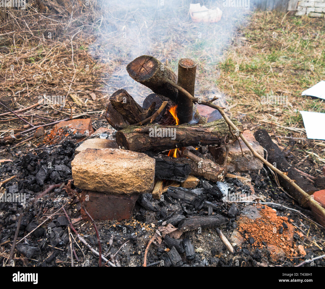 Fire on the village backyard. With a pile of burnt coal and old brick ...