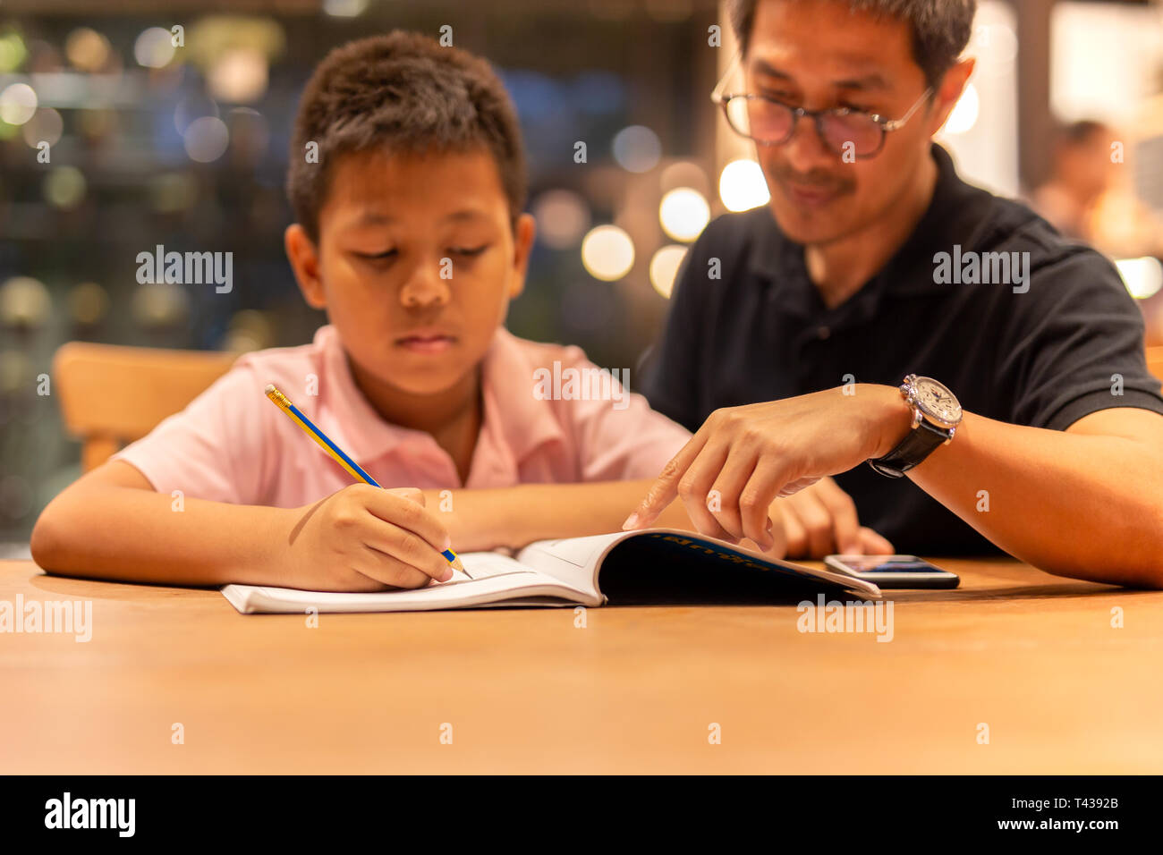 Boy doing homework with father at home Stock Photo - Alamy