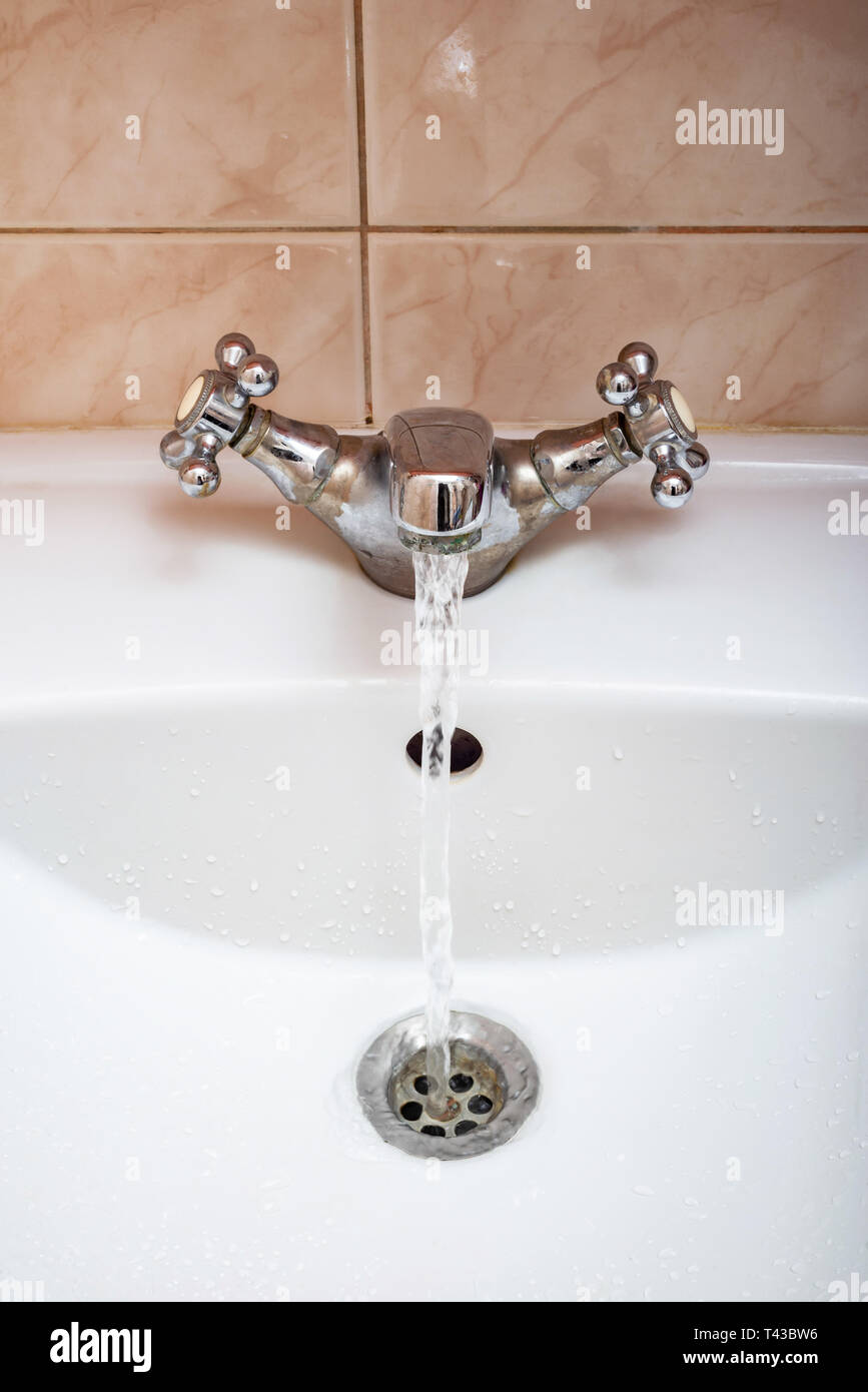 Vertical image of a tap with water flowing strongly under high pressure ...