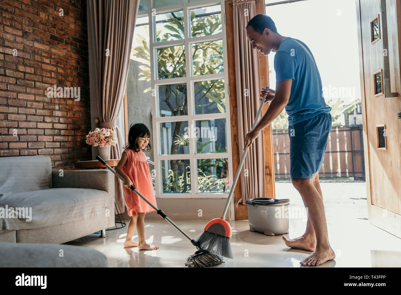 father and daughter clean up the house together sweep the floor Stock ...