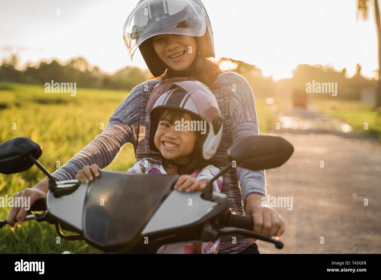 mom and her child enjoy riding motorcycle scooter in country ride road ...