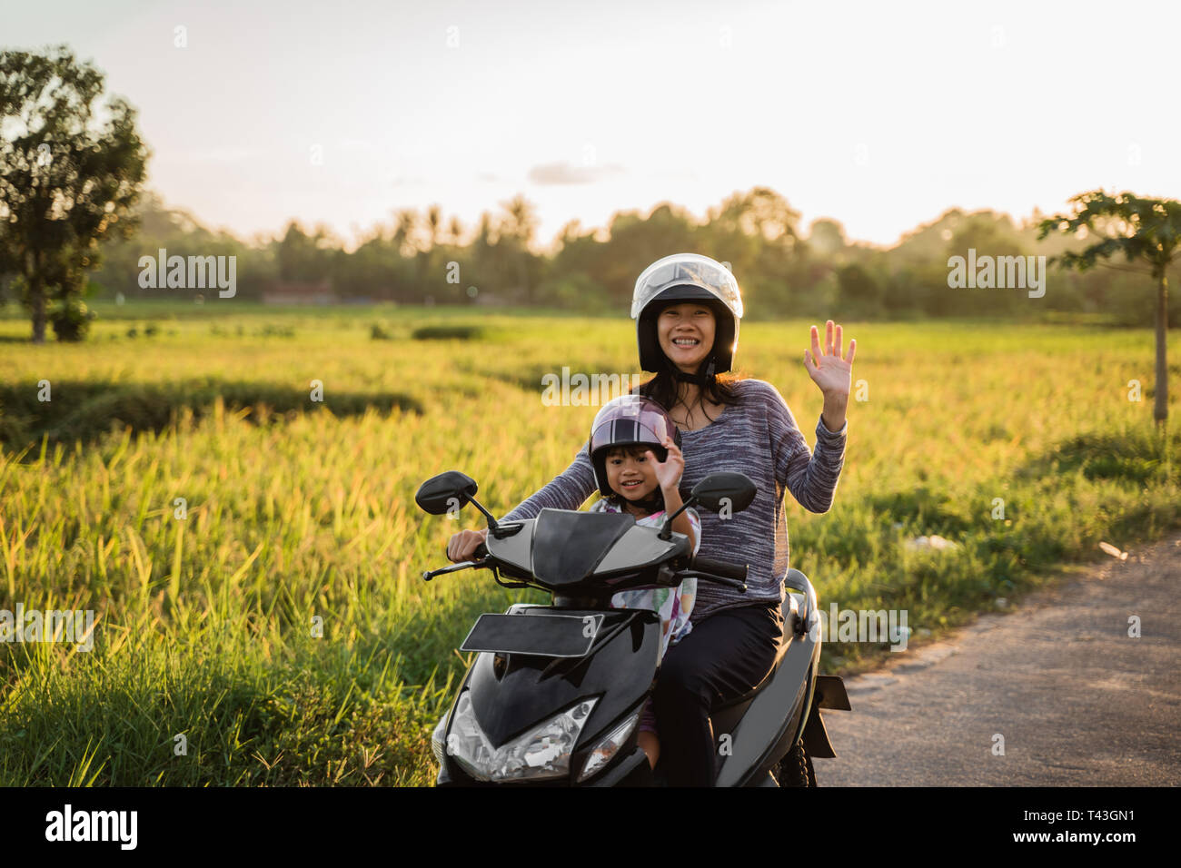 mom and her child enjoy riding motorcycle scooter in country ride road ...