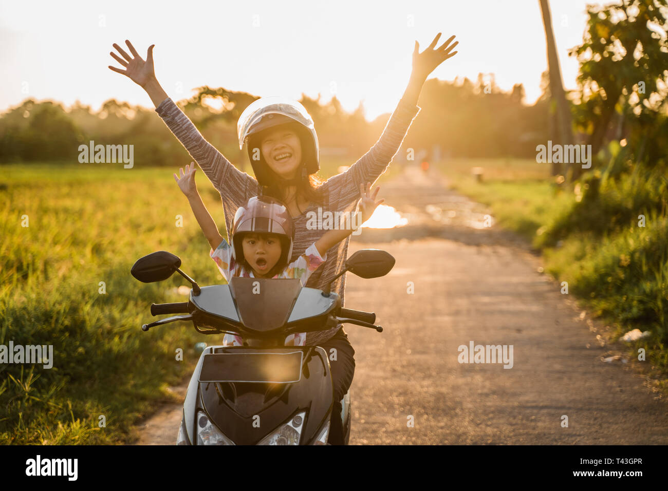 mom and her child enjoy riding motorcycle scooter in country ride road ...