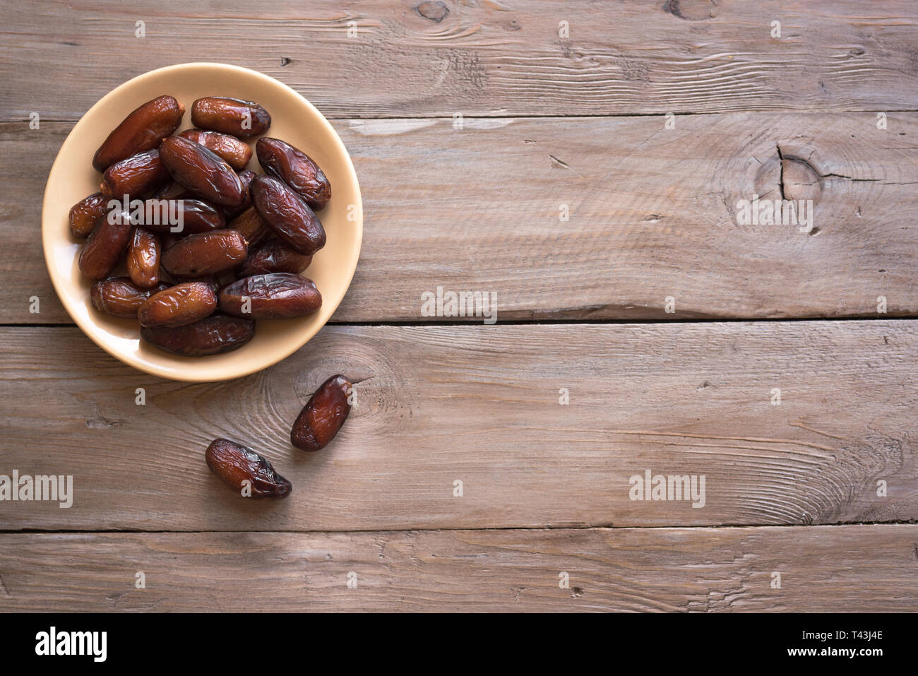 Dates on plate on wooden background, top view, copy space. Organic ...