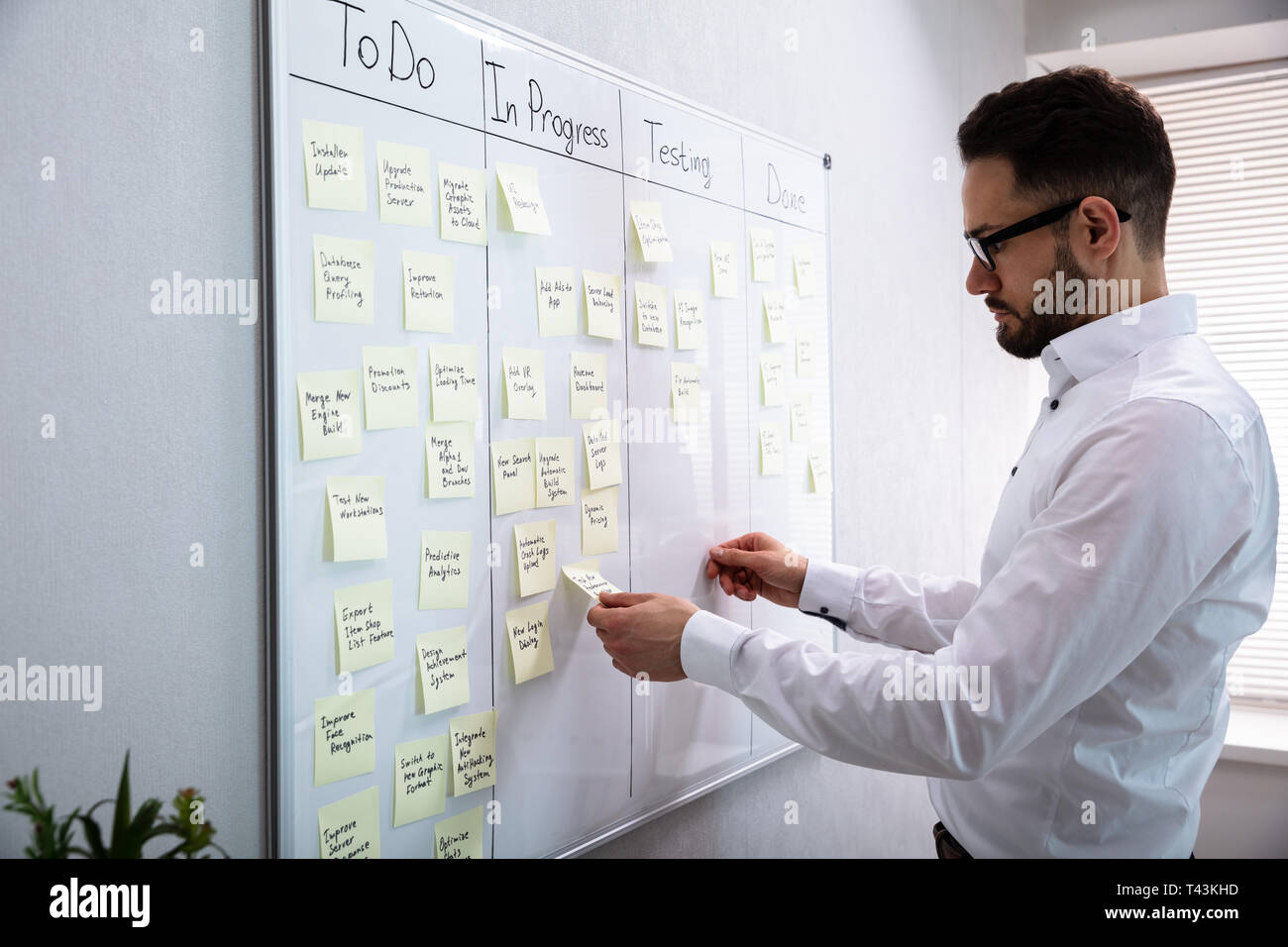 Side View Of Businessman Writing On Sticky Notes Attached To White ...