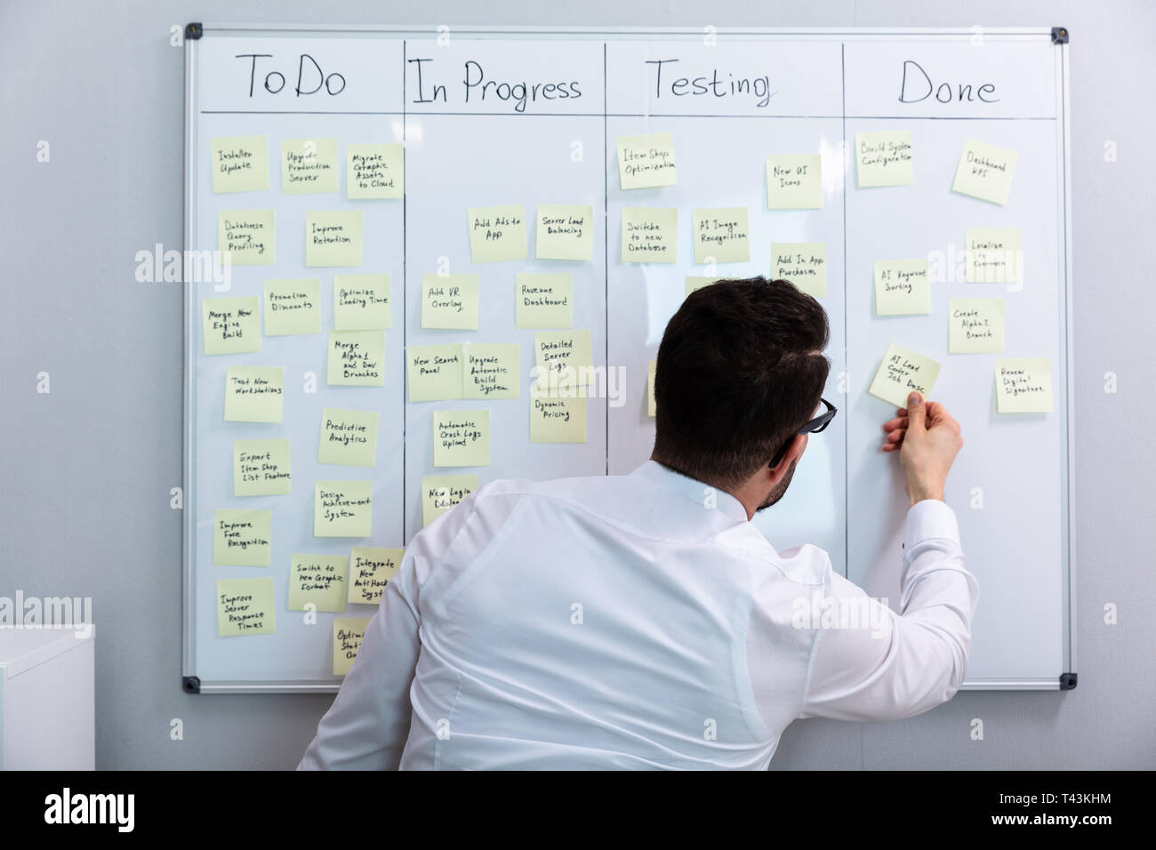 Side View Of Businessman Writing On Sticky Notes Attached To White ...