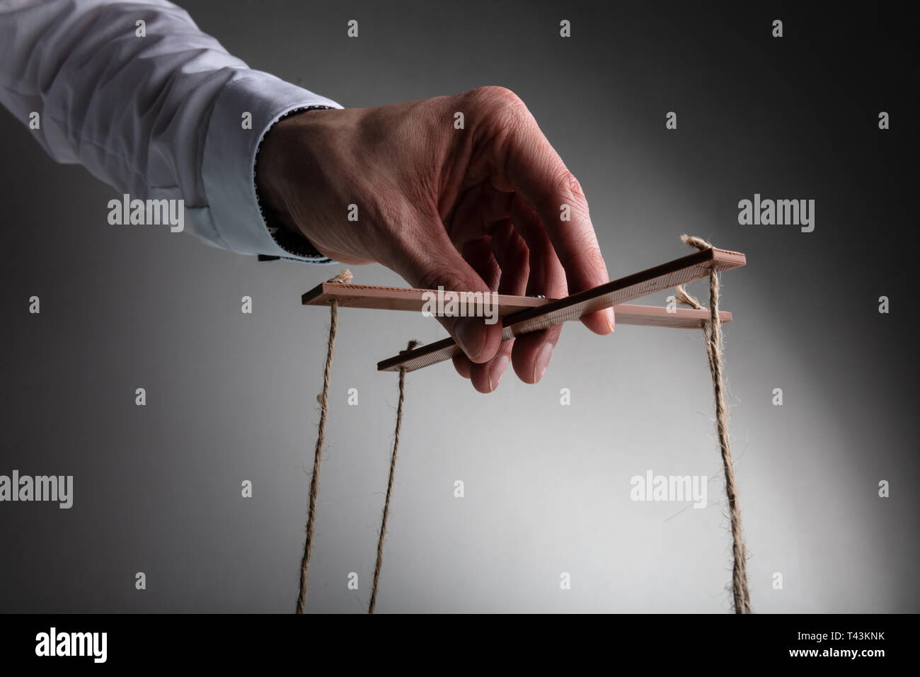 A Businessman's Hand Manipulating Marionette With String Against Gray ...