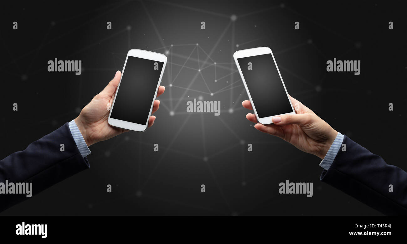 Close up of two hands holding smartphones to each other, wireless ...
