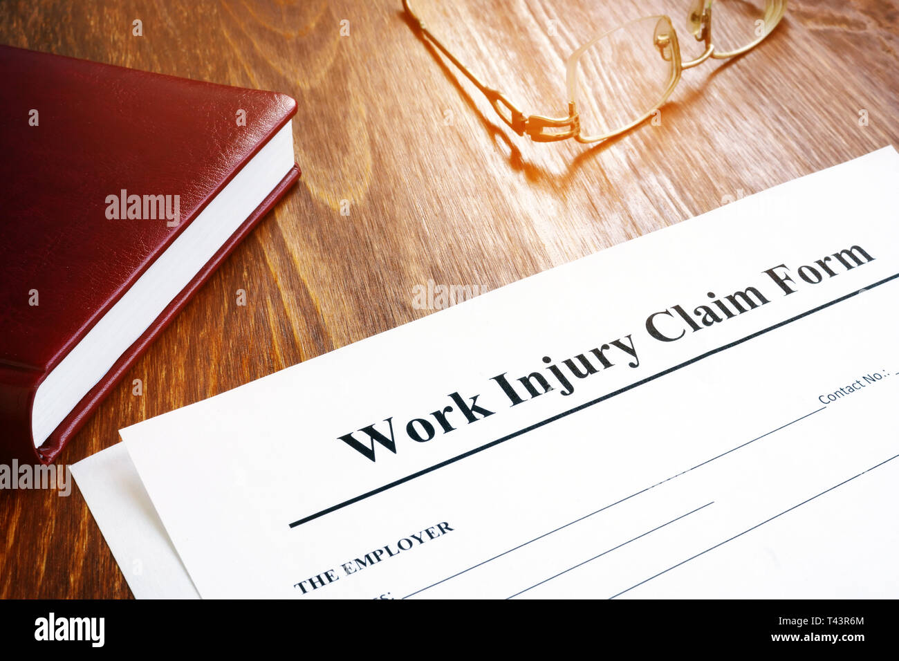 Work injury claim form and glasses on desk Stock Photo - Alamy