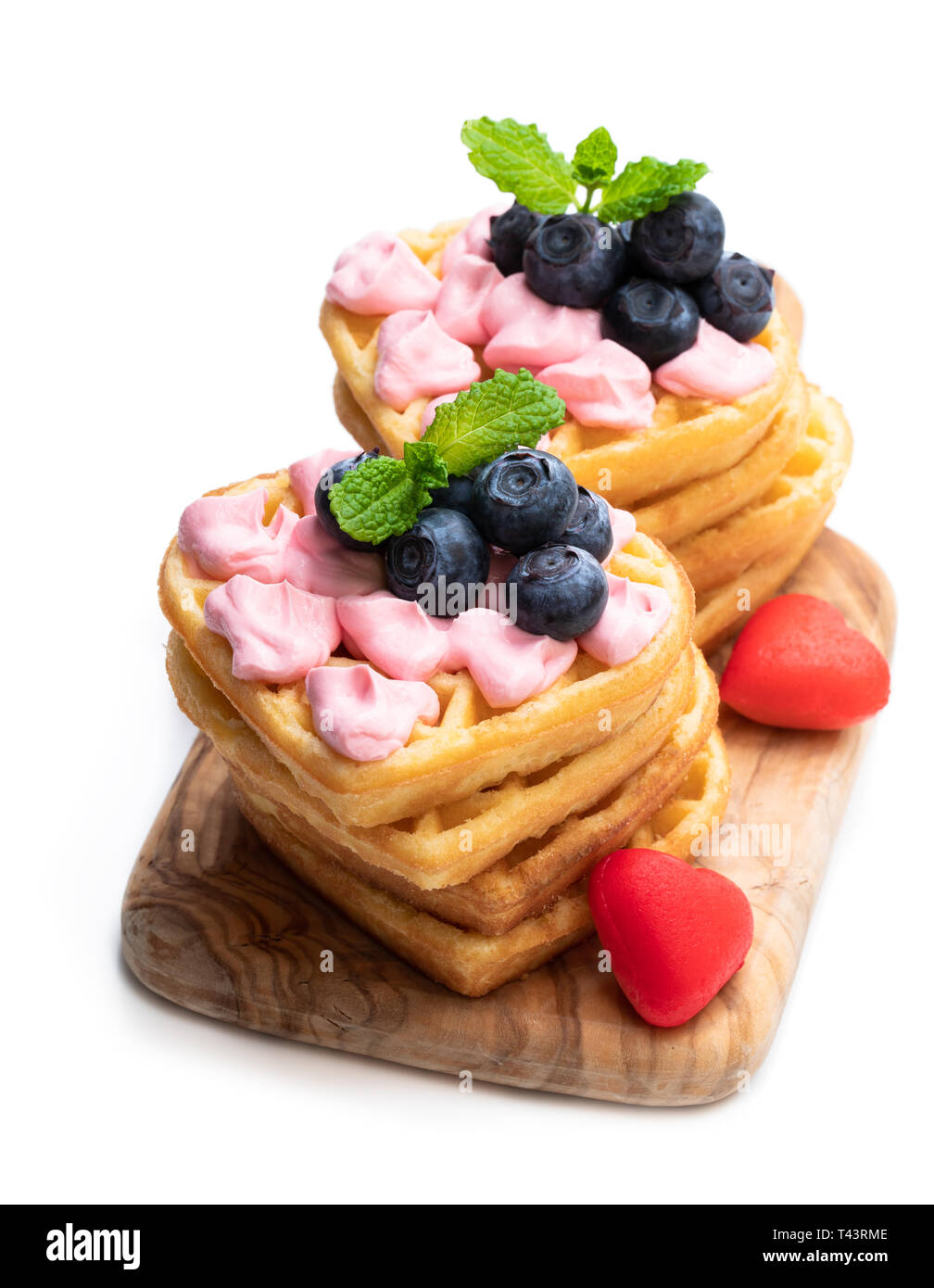 Stack of heart shaped waffles with pink cream and blueberry isolatedon ...