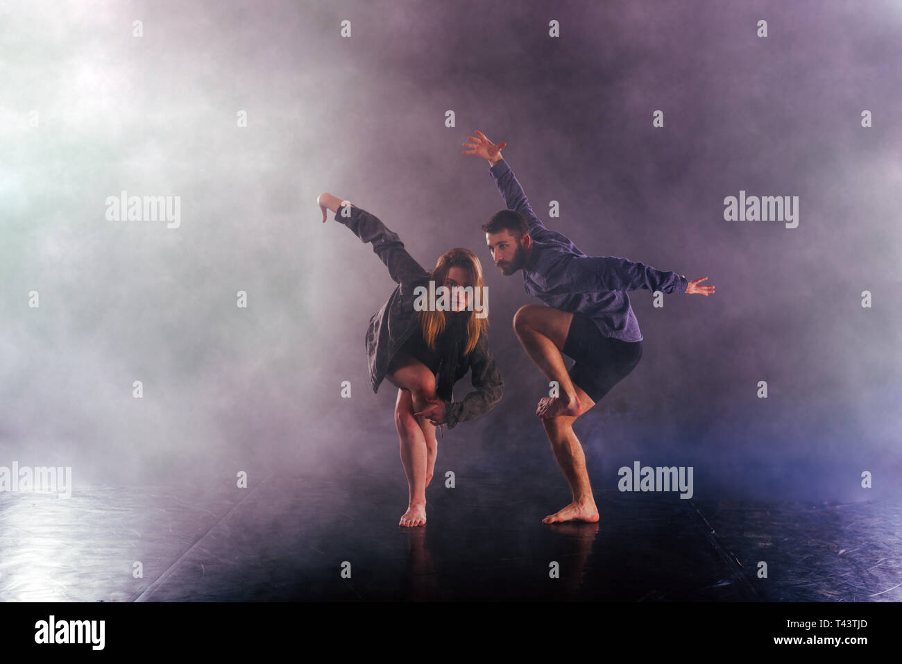Two modern dancers stretching their shoeless feet high in the air ...