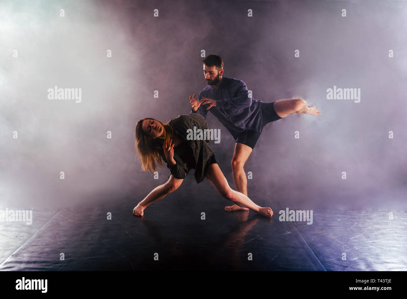 Two modern dancers stretching their shoeless feet high in the air ...