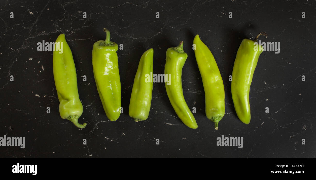Top down view, green pointed peppers on black board Stock Photo - Alamy