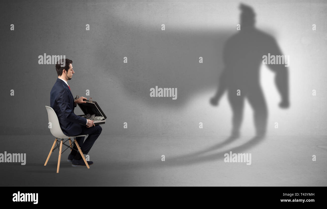 Humble businessman staying and offering stuffs to a superhero shadow ...