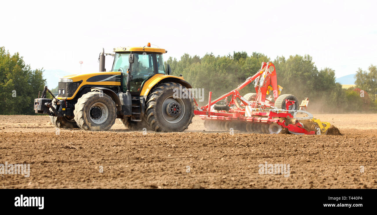Tractor pulling ploughing / sowing trailer over dry field Stock Photo ...