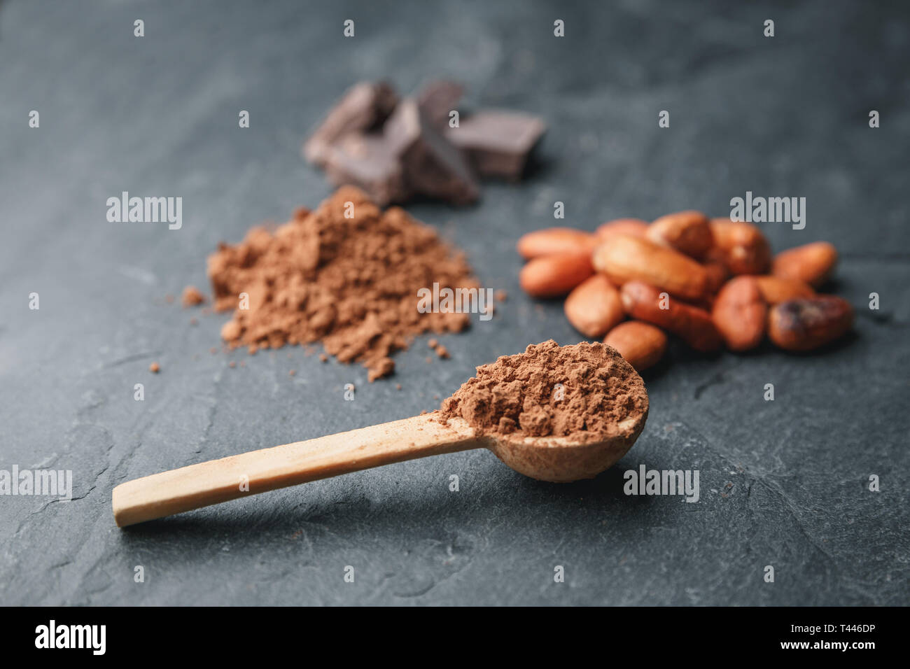 Organic cacao beans, cacao powder in a wooden spoon and chocolate on a ...