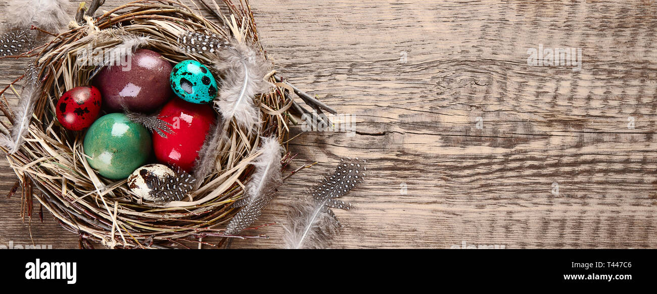 Easter eggs in nest on a wooden background. Happy Easter. Top view with ...