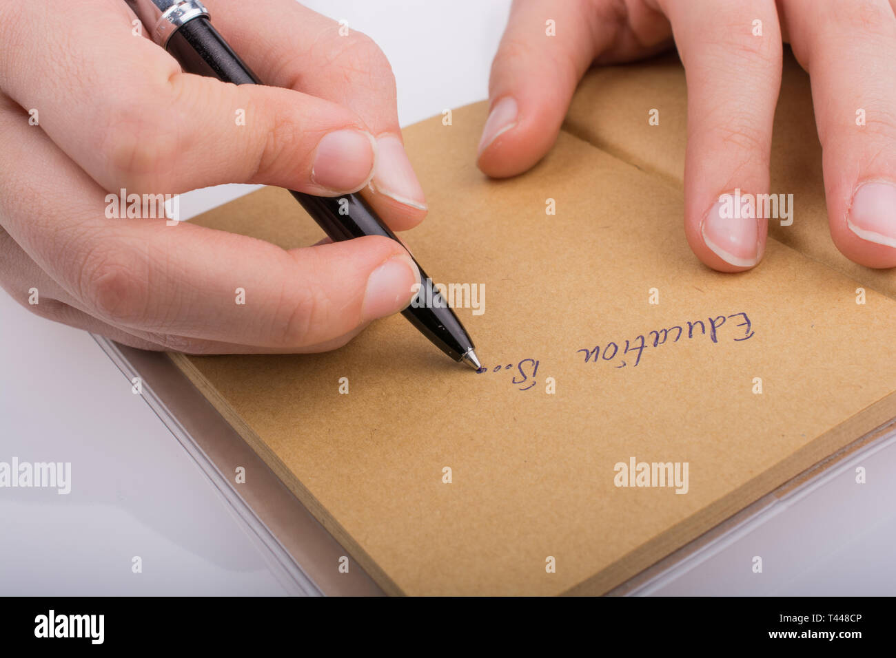 Hand writing 'Education is...' on a notebook Stock Photo - Alamy