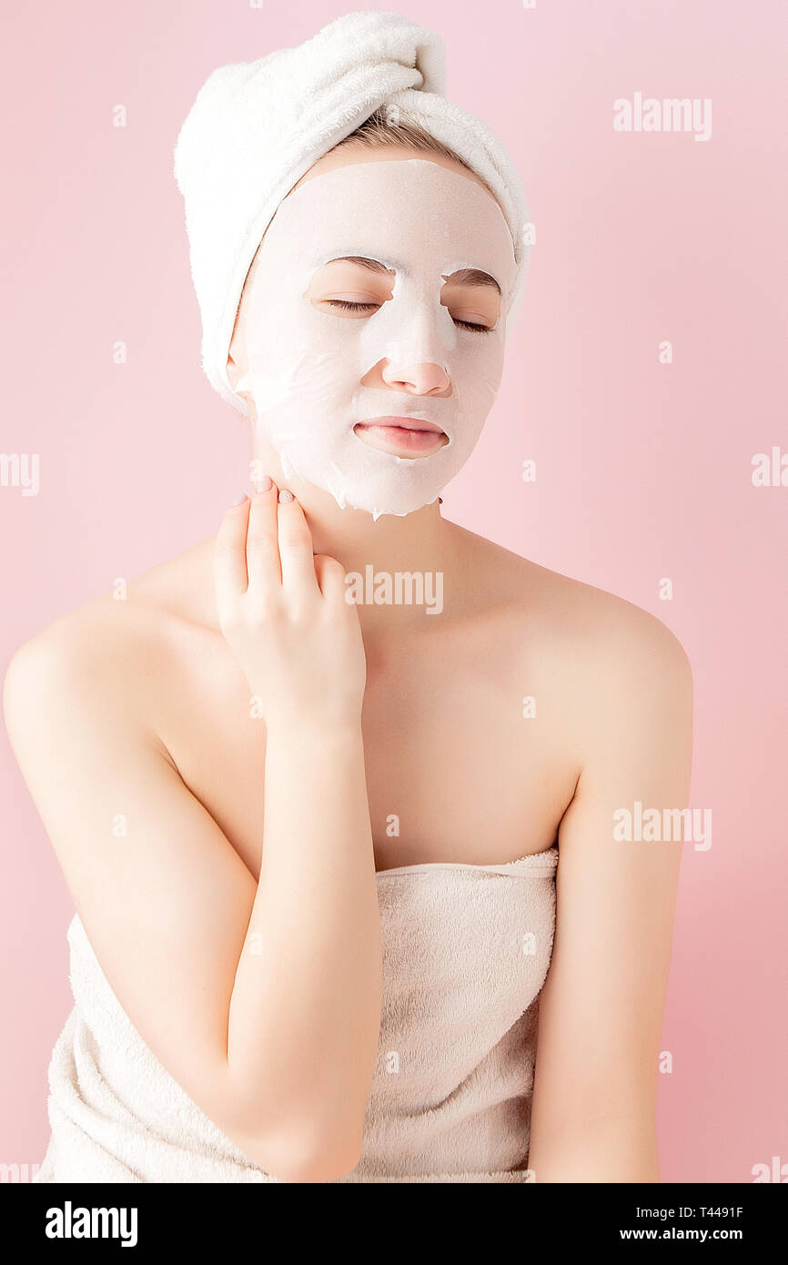 Beautiful young woman is applying a cosmetic tissue mask on a face on a ...
