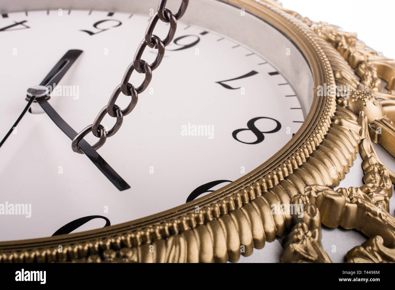 chain tied to minute hand of a clock and pulled on a white background ...