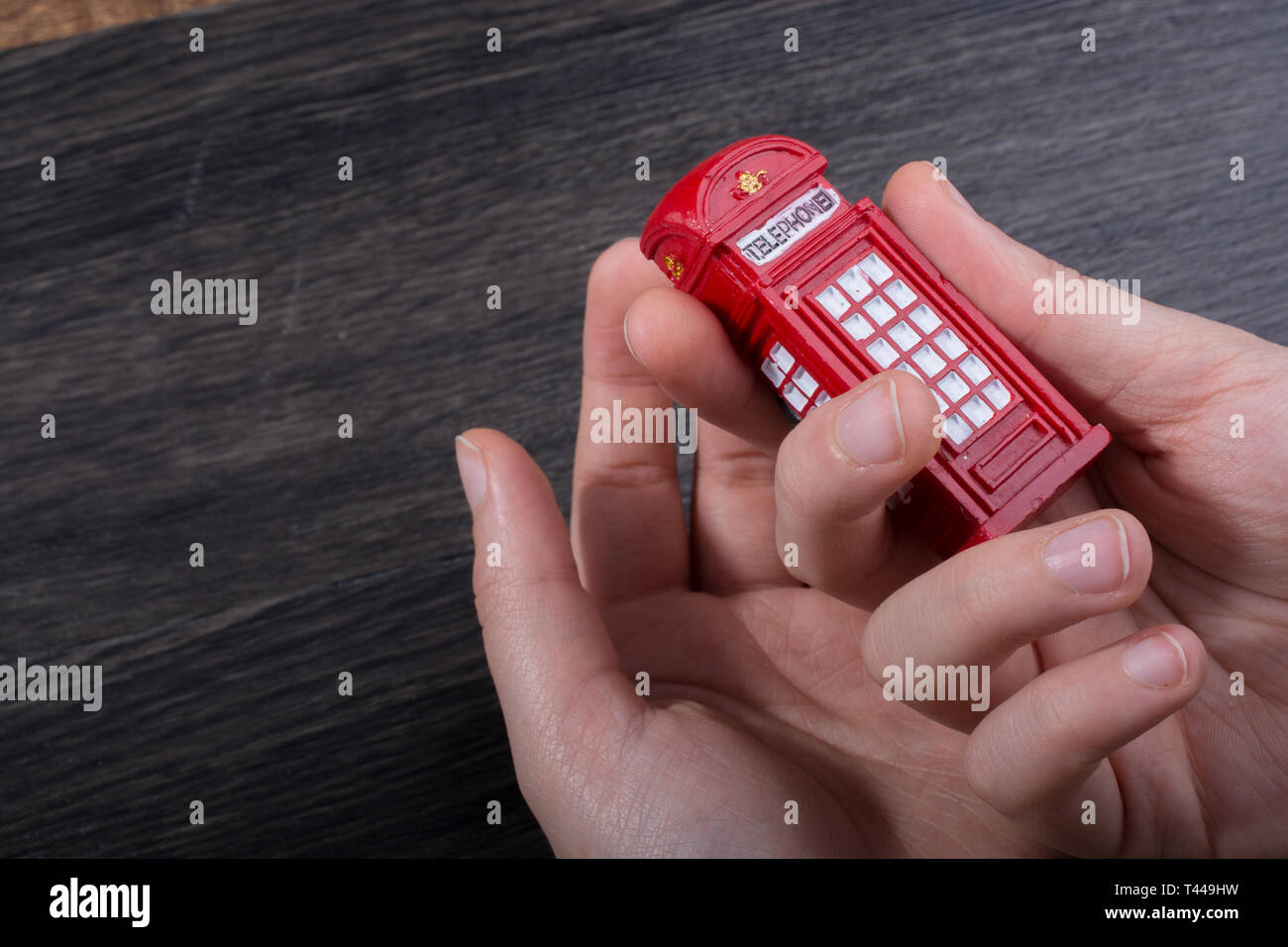 Hand holding a phone booth on a brown background Stock Photo - Alamy