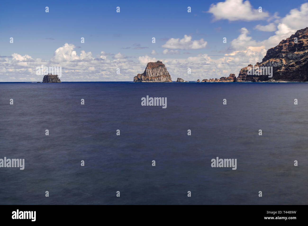 Roques de Salmor, volcanic rocks and cliff in Atlantic ocean,with blue sky and white clouds ...