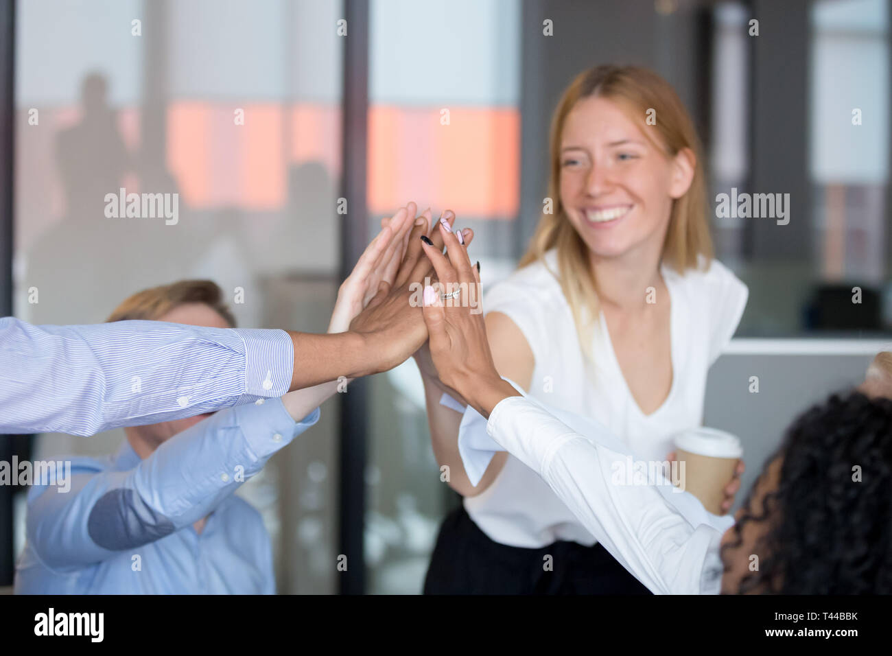 Happy multicultural employees give high five together, focus on hands ...