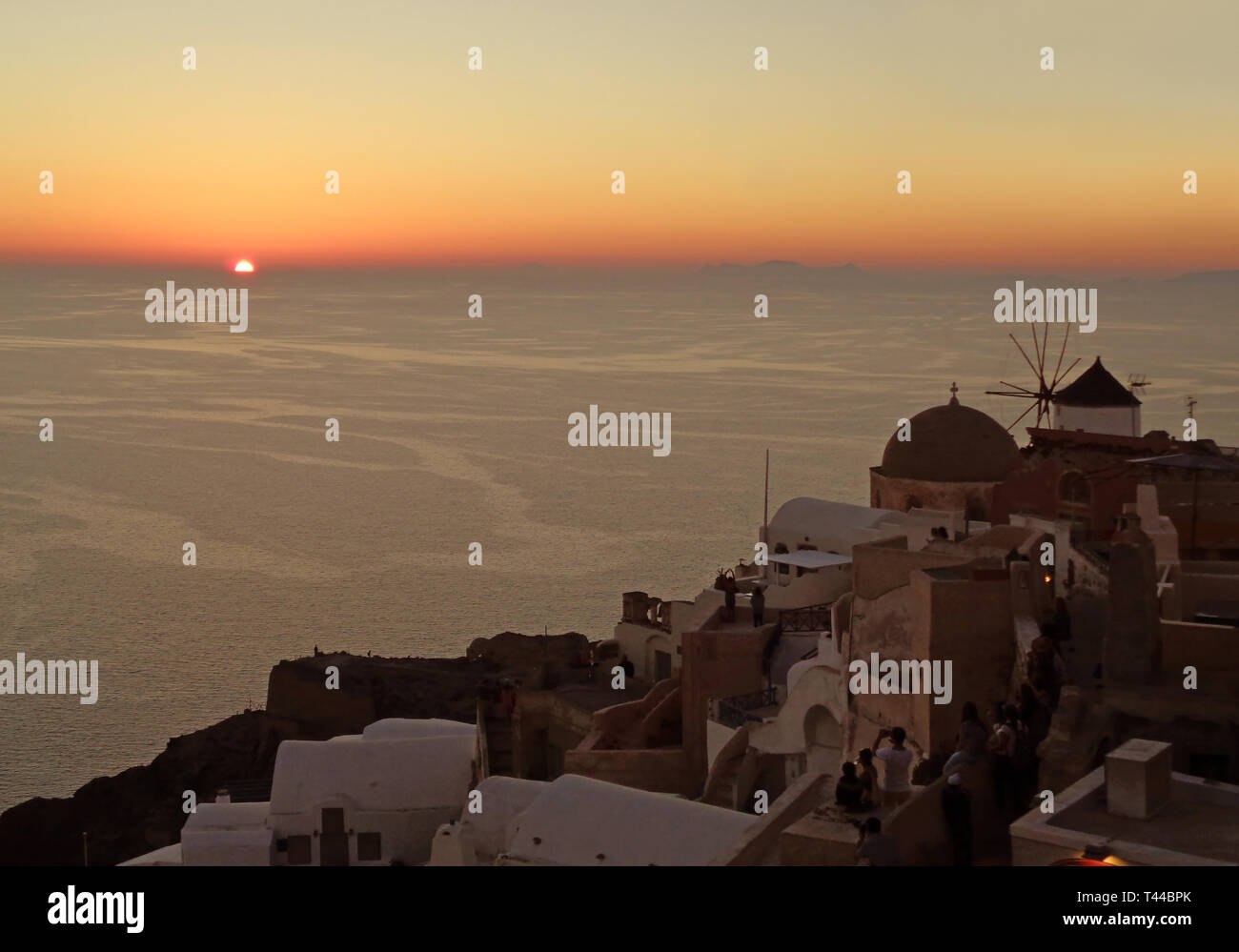 The sun setting on the horizon of Aegean sea, Oia village, Santorini ...