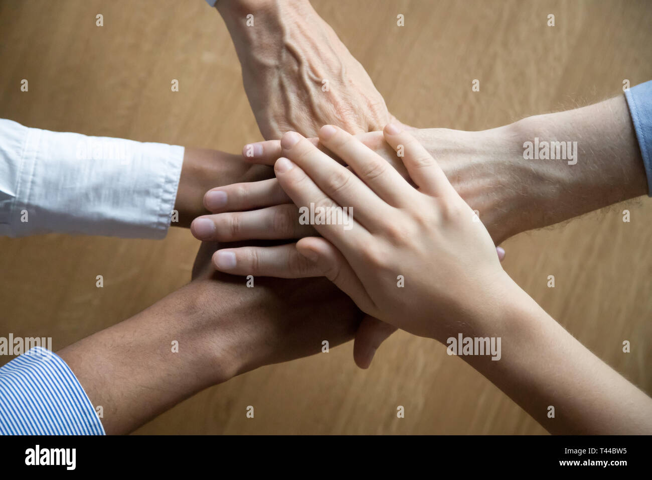 Multicultural employees stacking hands together engaged in team ...