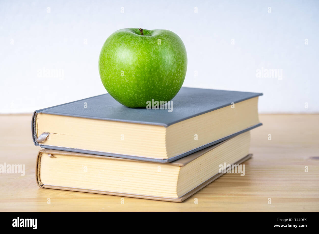 Two books and green apple on the wooden table, education Stock Photo ...
