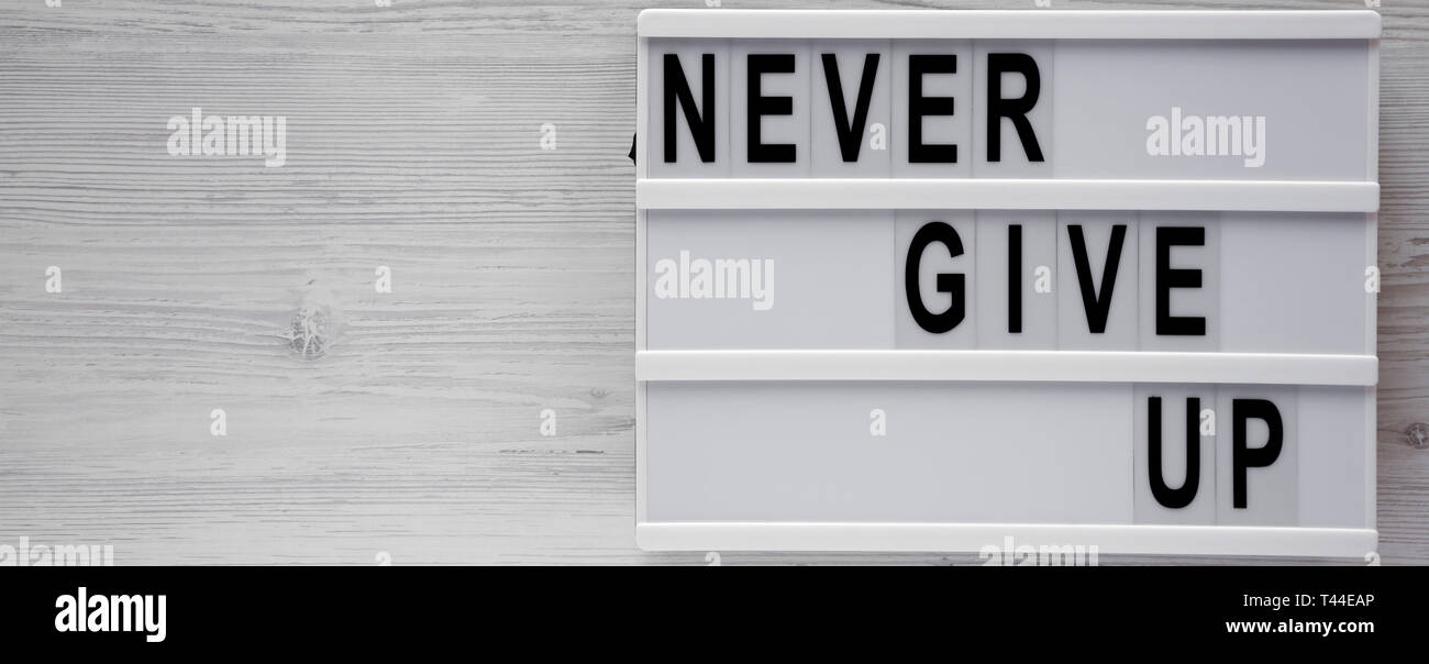 'Never give up' words on lightbox over white wooden background, top ...