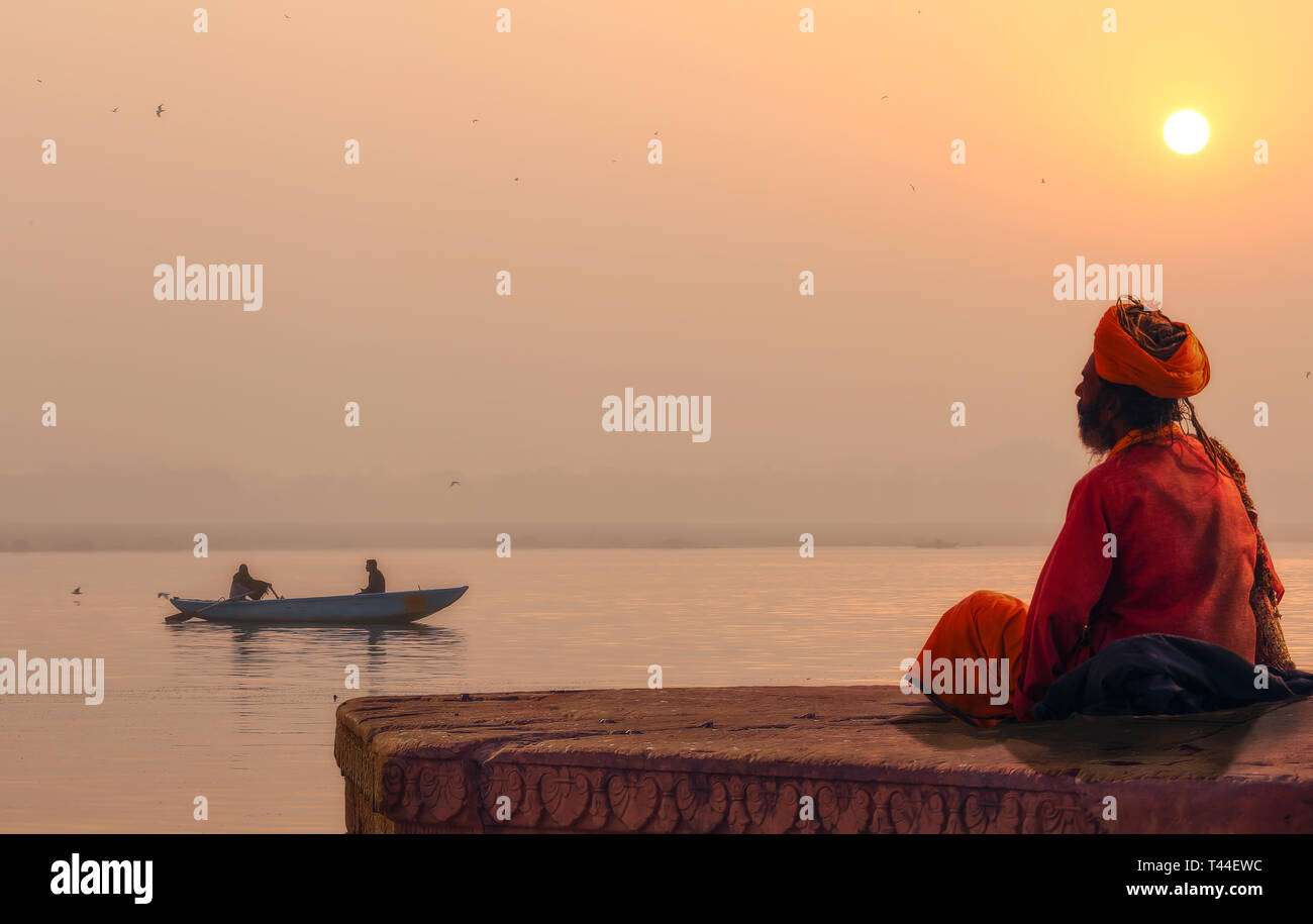Hindu sadhu baba in meditation at the Ganges river bank at sunrise with ...