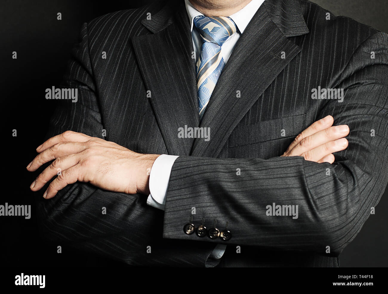 close up of a man in a suit with his hands arms crossed Stock Photo - Alamy