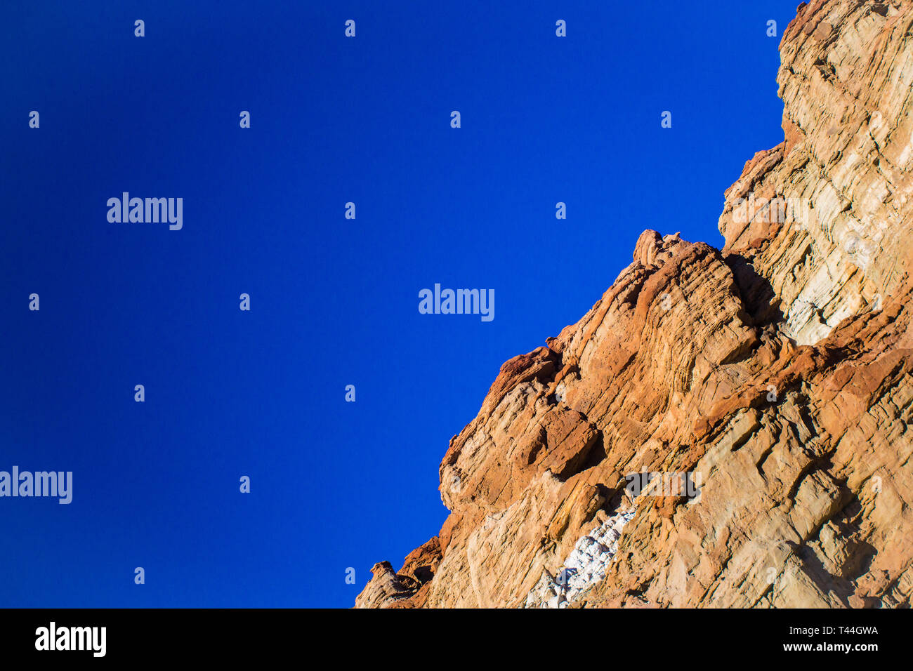 Orange colored rock wall in the desert under a bright blue sky Stock ...