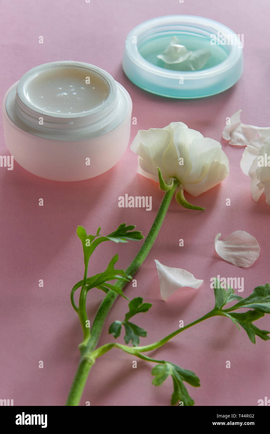 Organic skin care product and delicate flowers on pink background ...