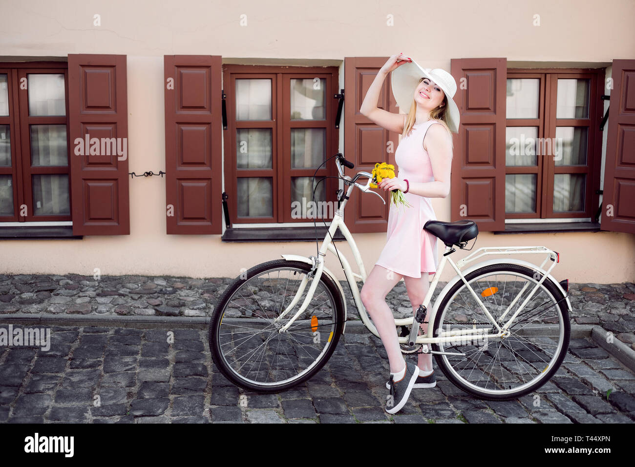 beautiful girl in a pink dress with flowers on a bicycle. smiling ...
