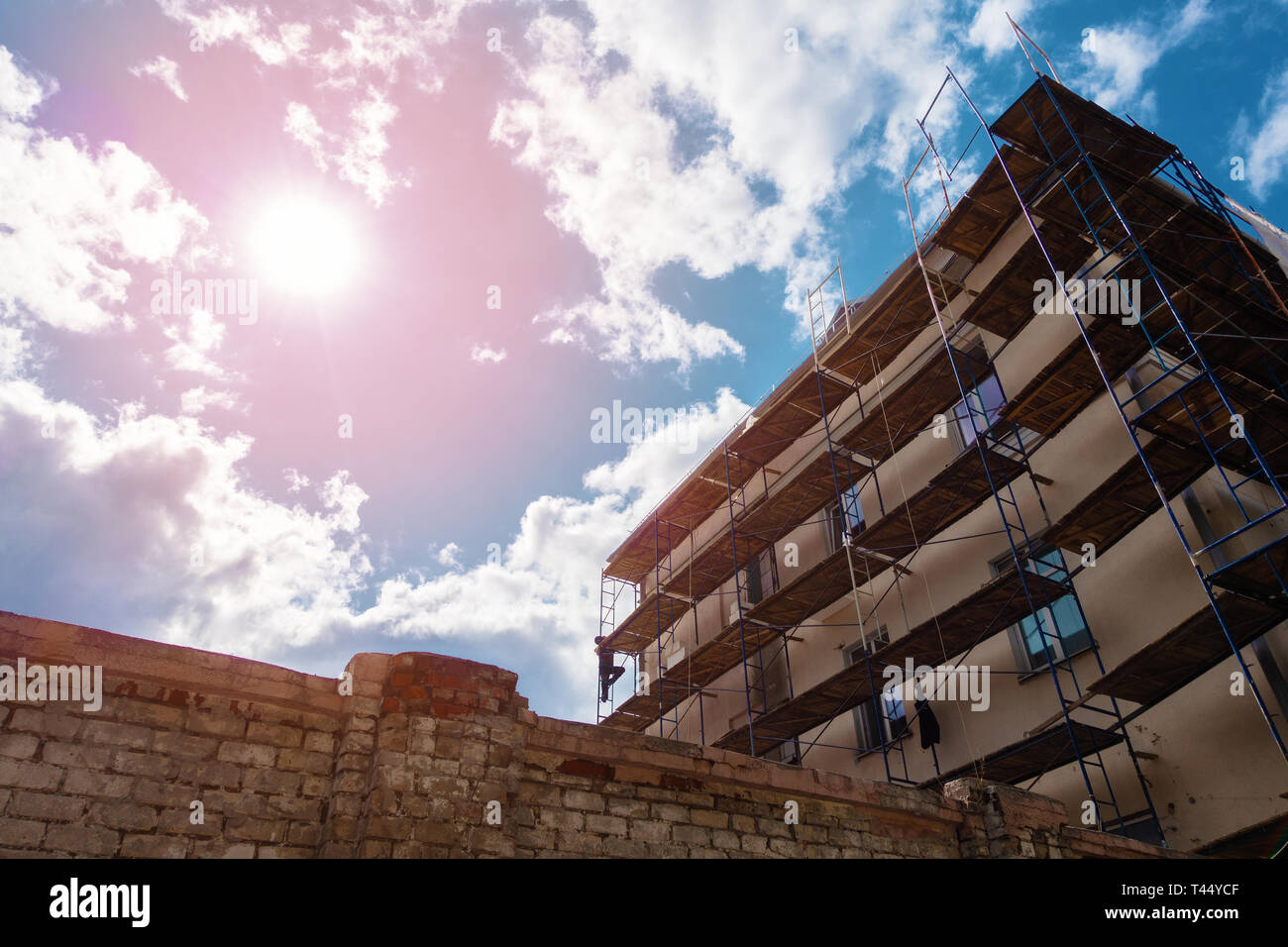 repair of building facade building in the city. the worker climbs up ...