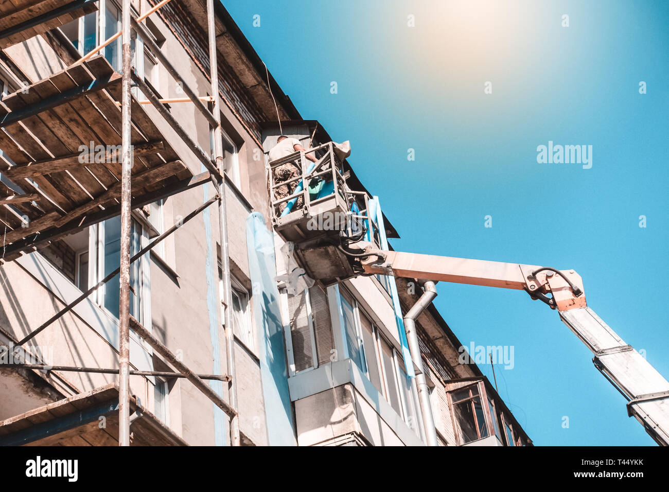 workers repair the building on high crane. men pull the net and ...