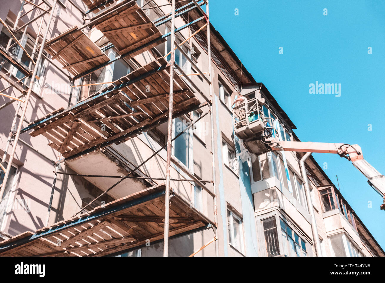 workers repair the building on high crane. men pull the net and ...