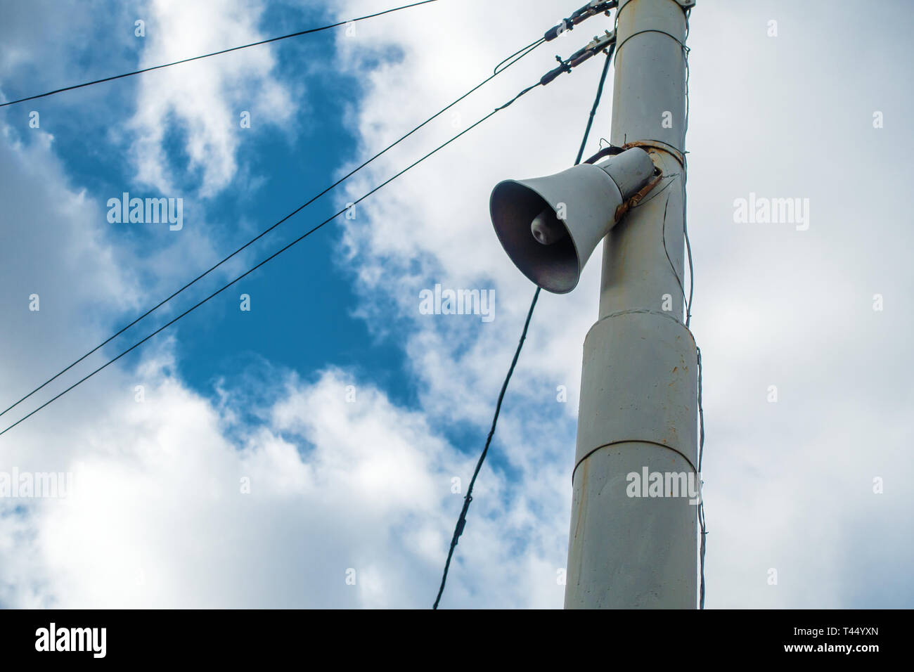 megaphone hanging on a pole with wires. against the sky with clouds ...