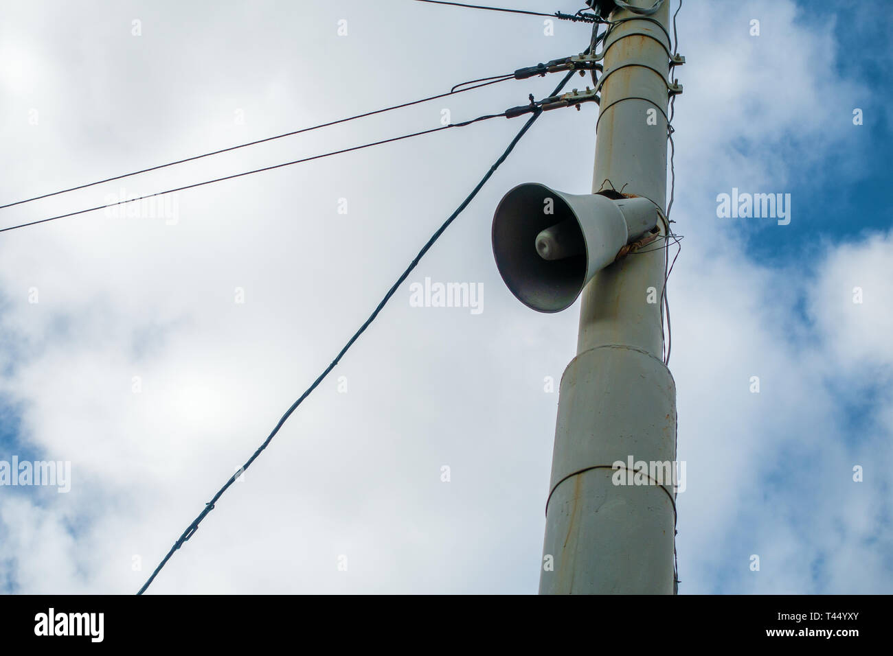 megaphone hanging on a pole with wires. against the sky with clouds ...