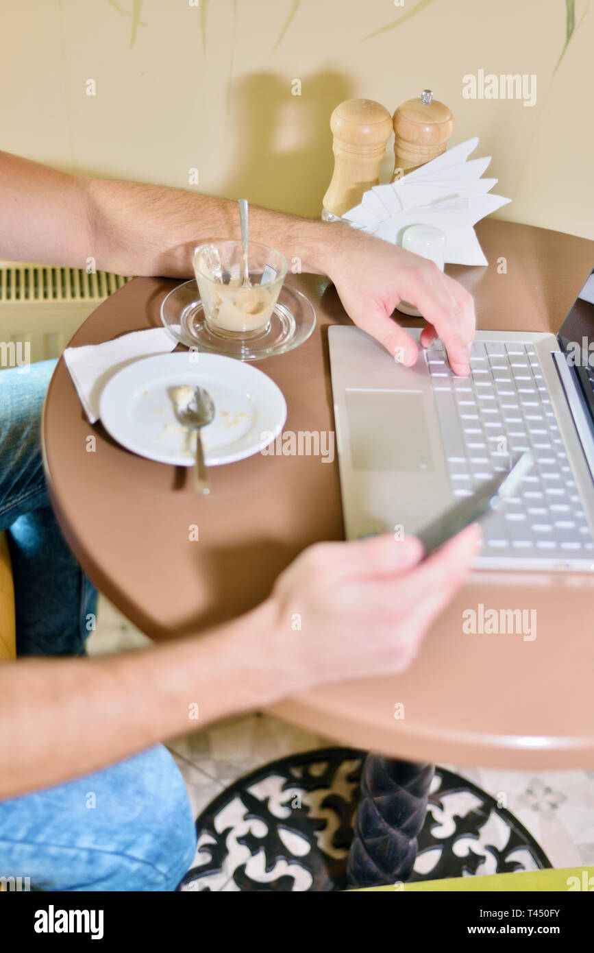young guy in cafe working behind laptop. the man has eaten and is ...