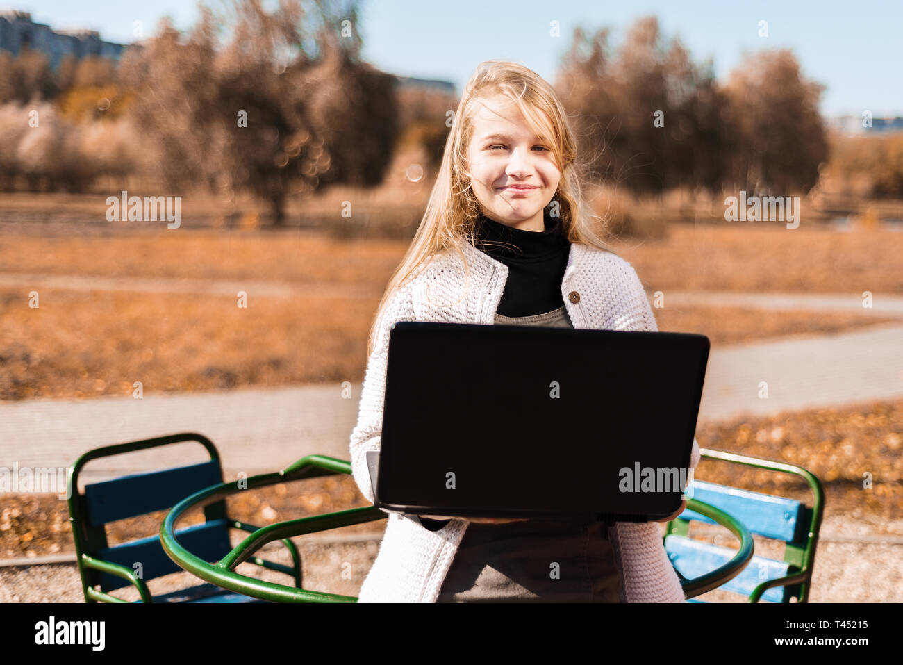 beautiful student sits on the carousel for a laptop. student doing ...