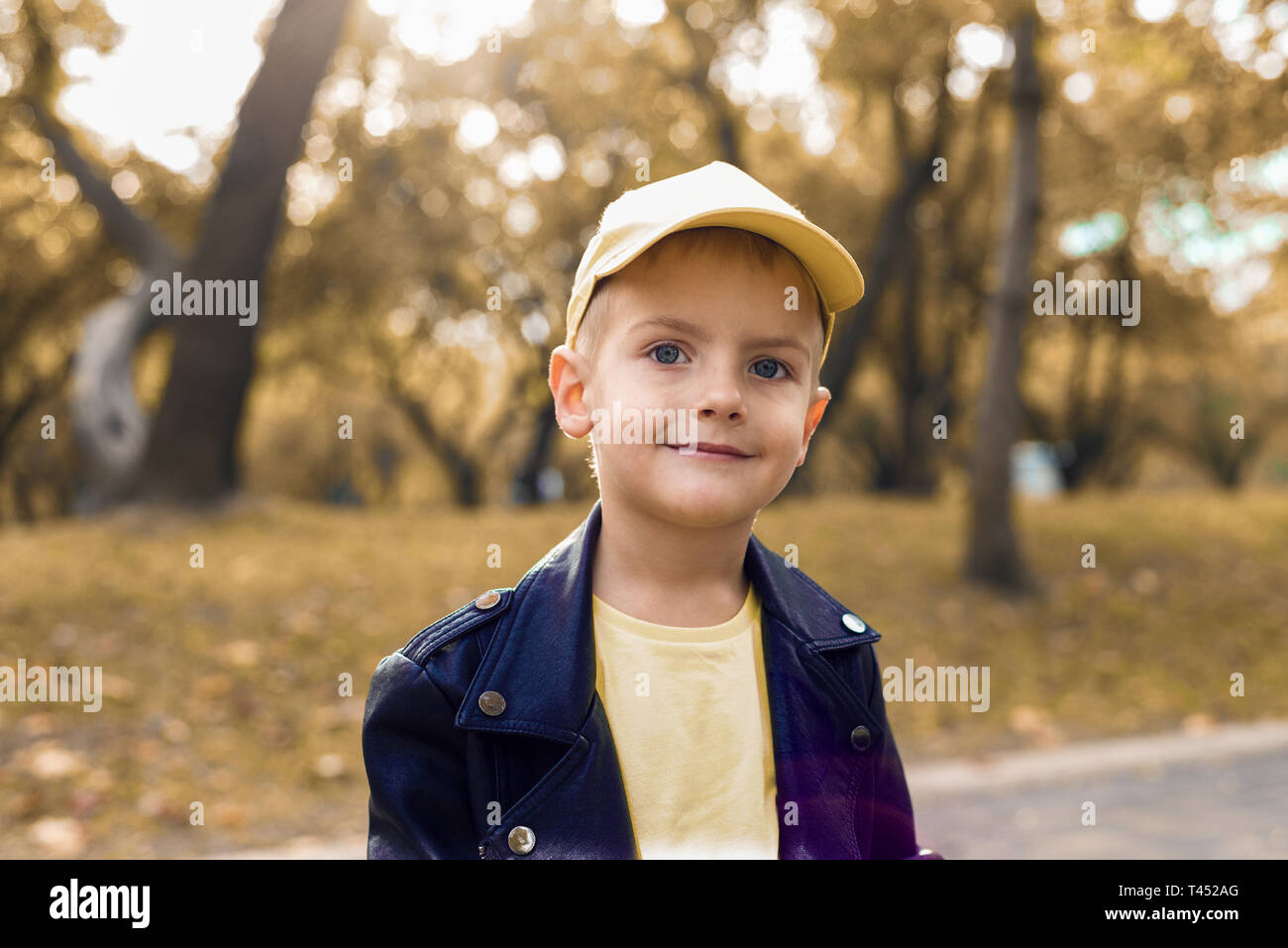 autumn portrait of cute little boy in a yellow cap and black leather ...